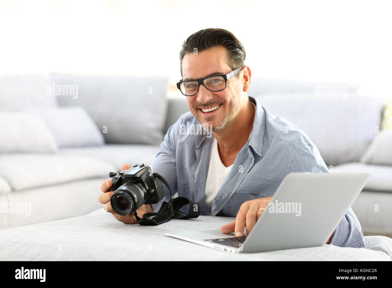 Man at home using reflex camera and laptop Stock Photo - Alamy
