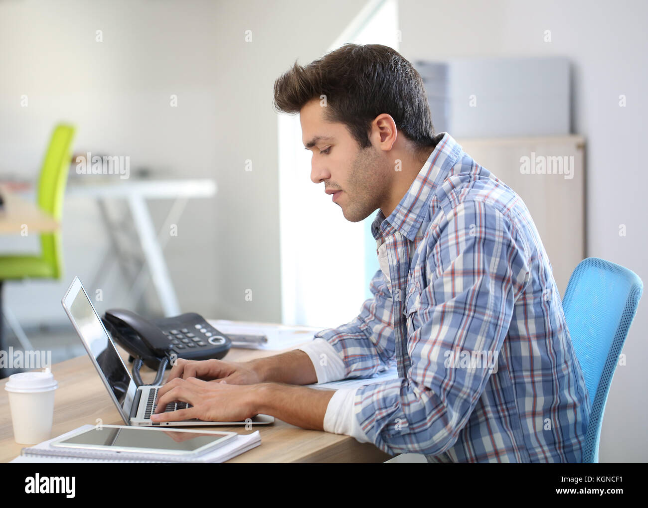 Young man in office working on laptop computer Stock Photo - Alamy