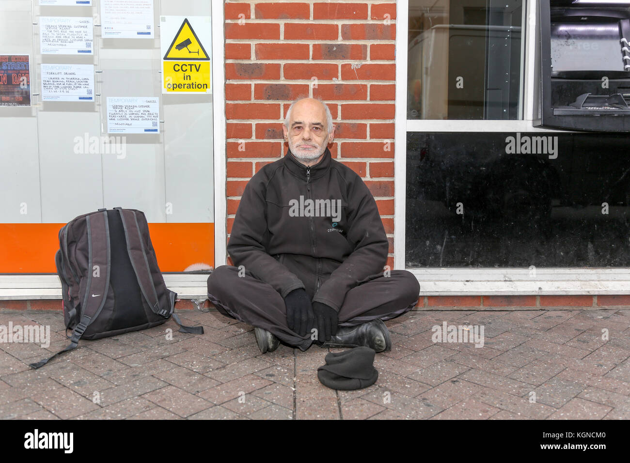 A homeless man sitting outside a shop Stock Photo - Alamy