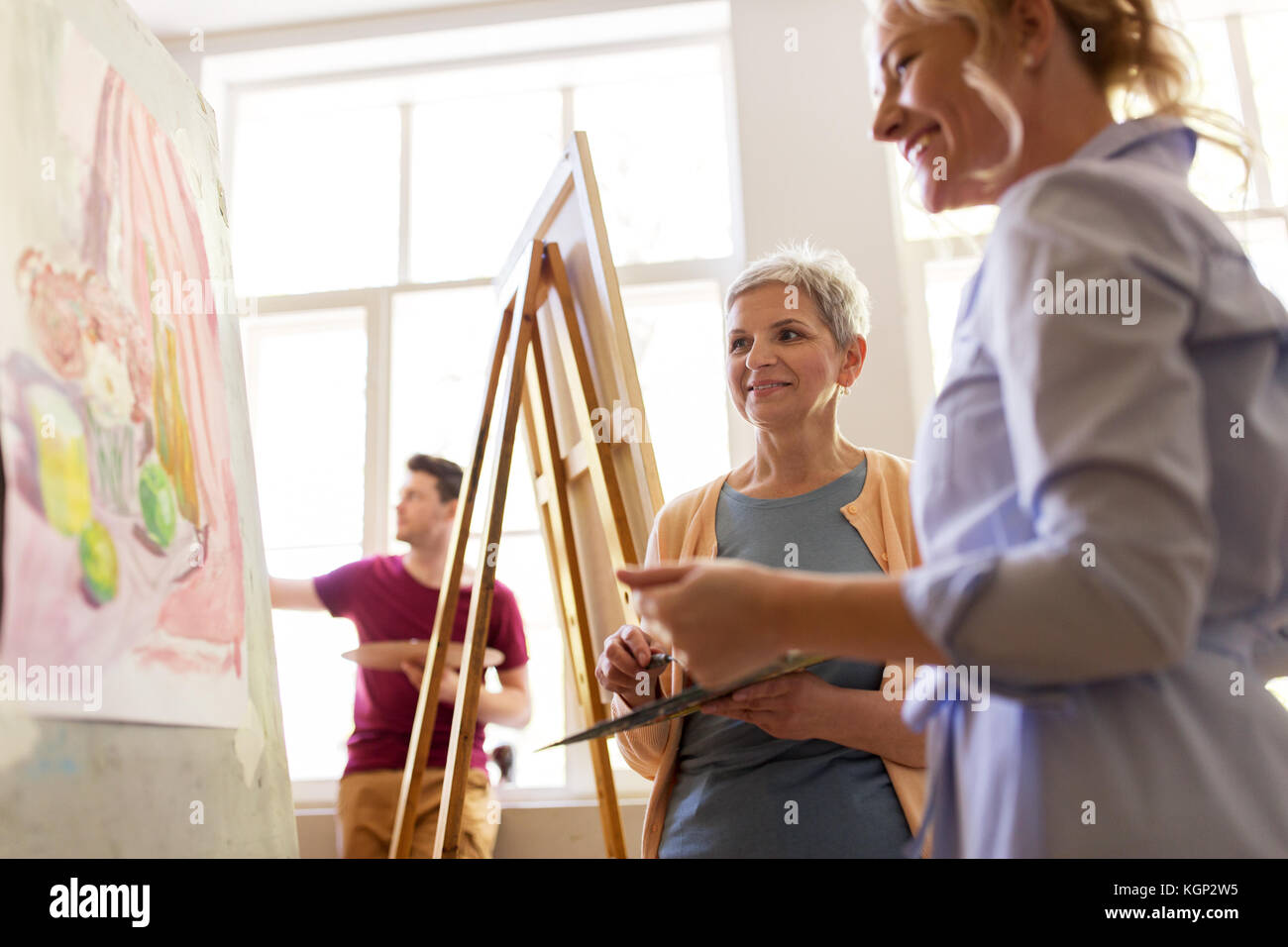 artists discussing painting on easel at art school Stock Photo - Alamy
