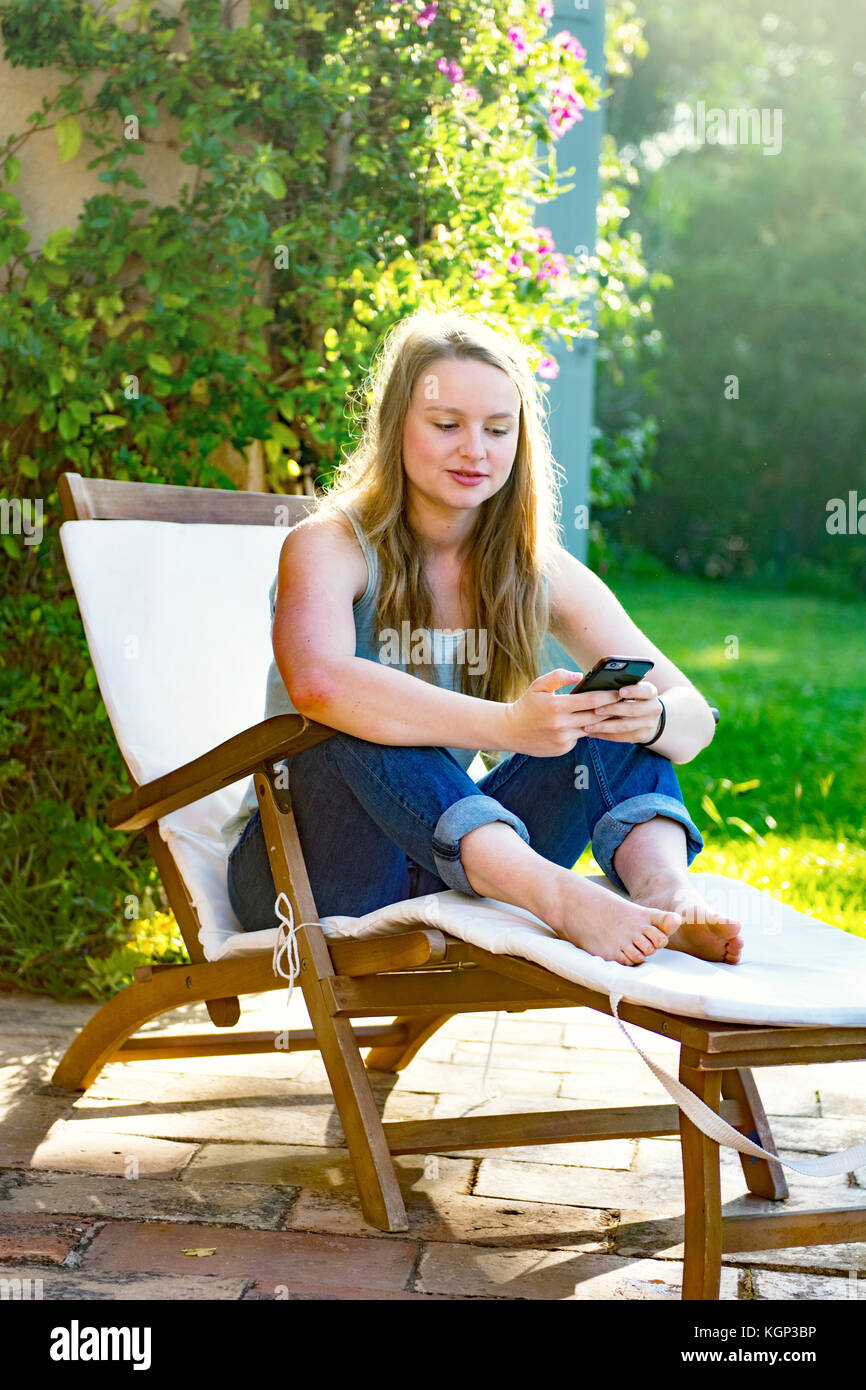 Young woman lounging with cell phone Stock Photo - Alamy