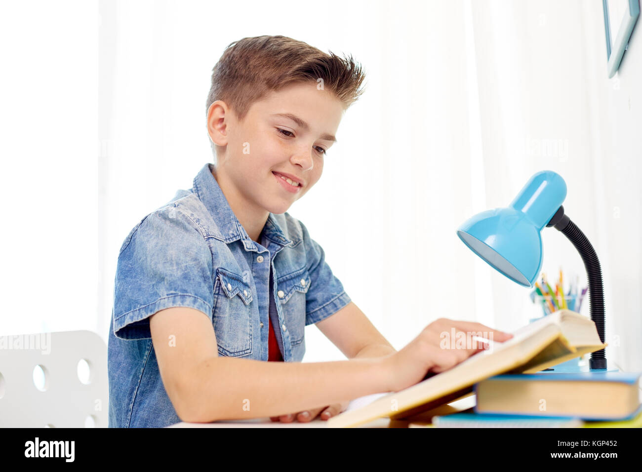 student boy reading book at home table Stock Photo - Alamy