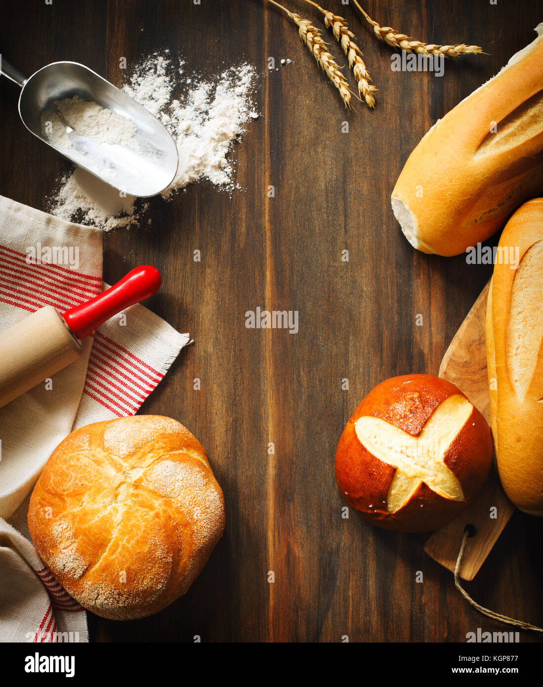 Assortment of baked bread, flour and roller pin on wooden background ...