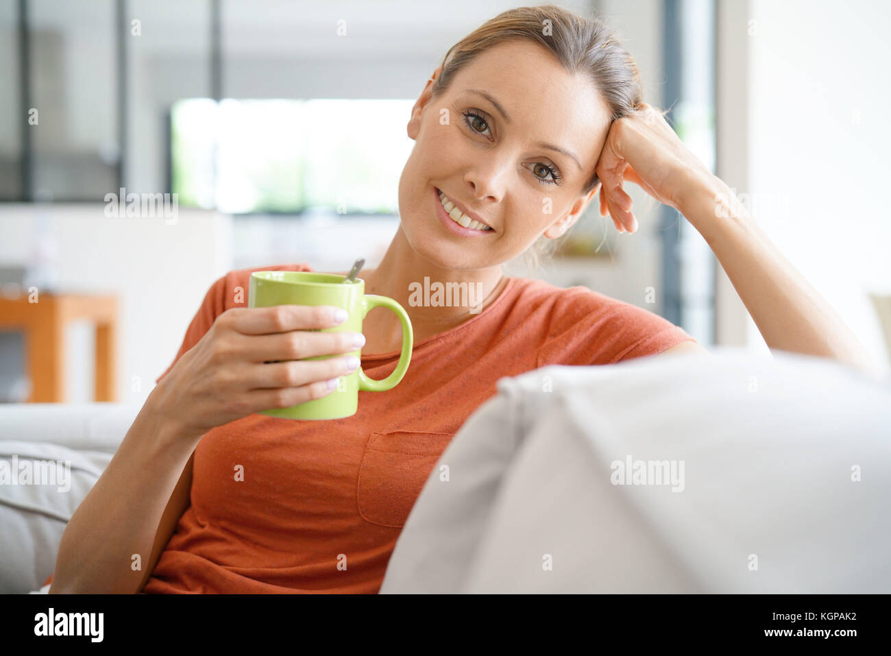 Cheerful woman relaxing in sofa and drinking tea Stock Photo - Alamy