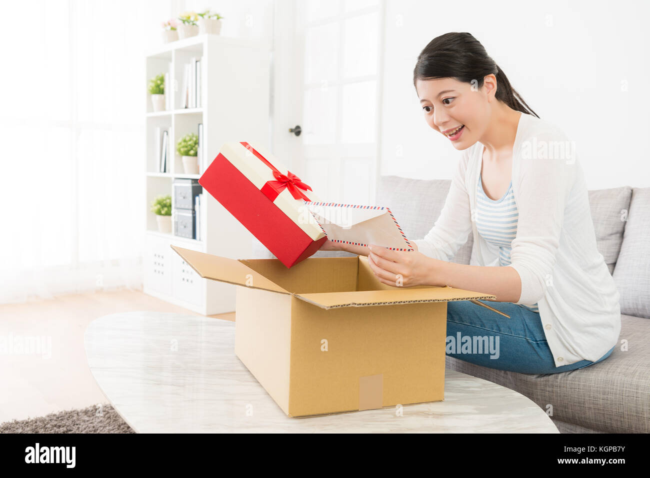 cheerful pretty lady unpacking personal parcel at home on her birthday ...