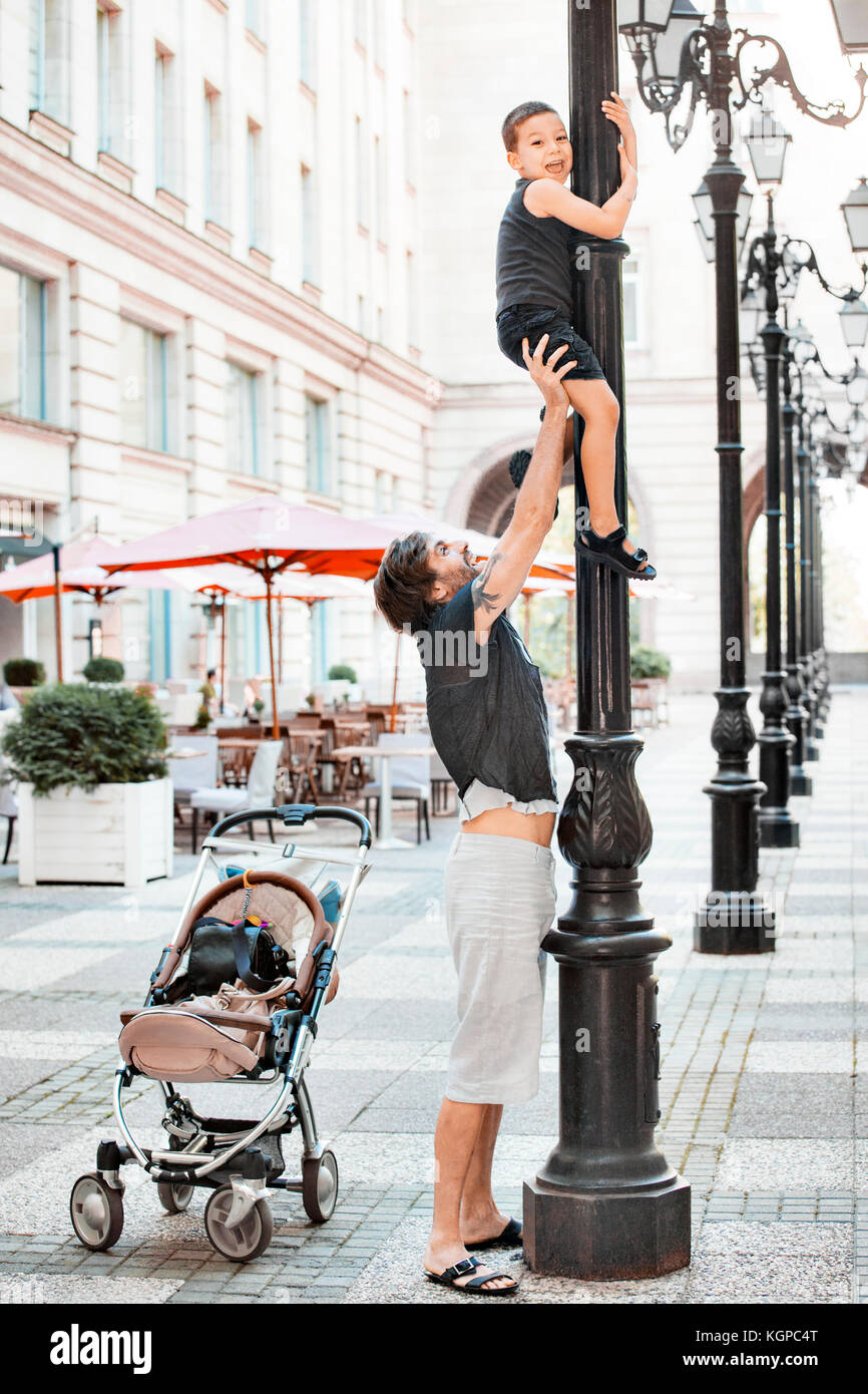 A handsome father is holding up his young boy on a street pillar Stock ...