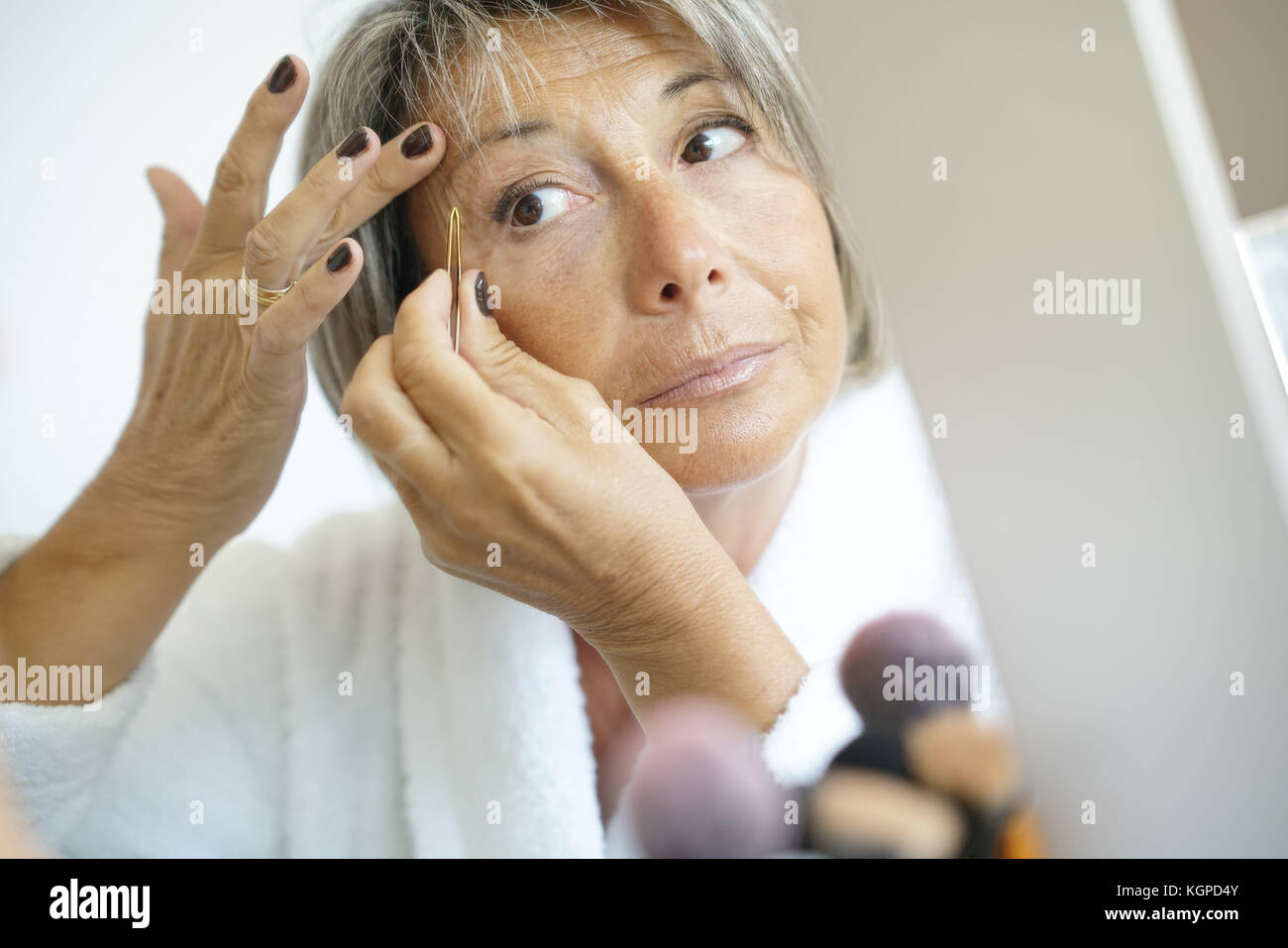 Senior woman removing eyebrows hair with tweezers Stock Photo - Alamy