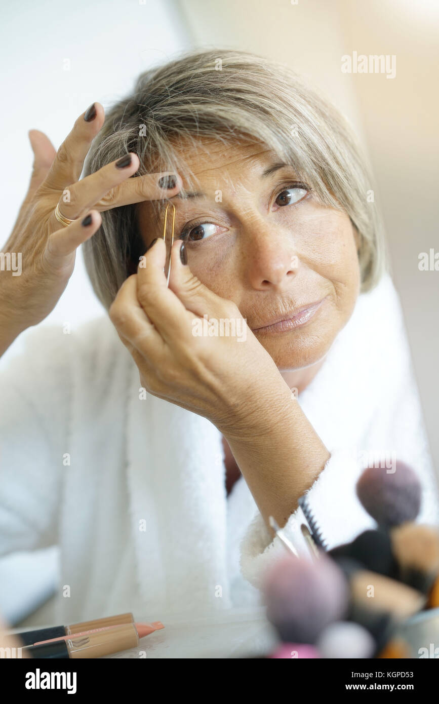 Senior woman removing eyebrows hair with tweezers Stock Photo - Alamy