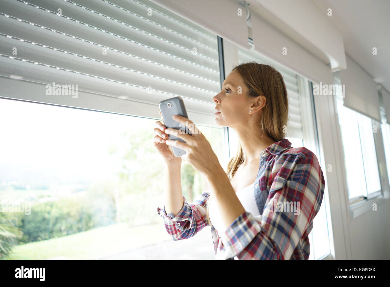 Woman using smartphone to control electric shutter Stock Photo - Alamy