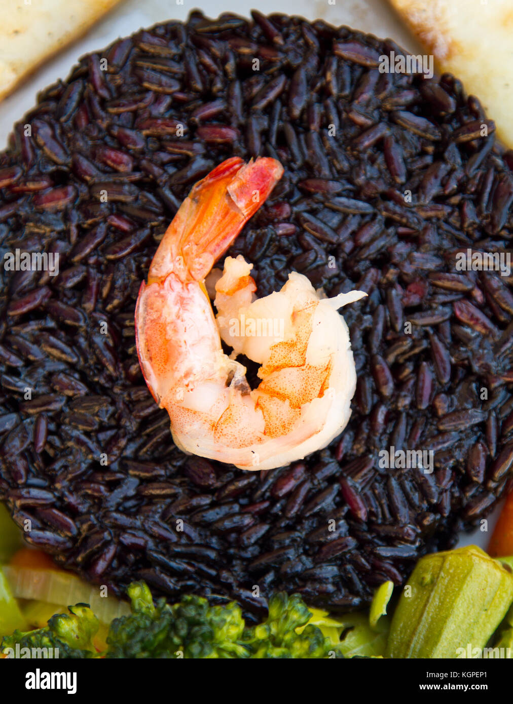 Fish with black rice, vegetables and prawn Stock Photo - Alamy