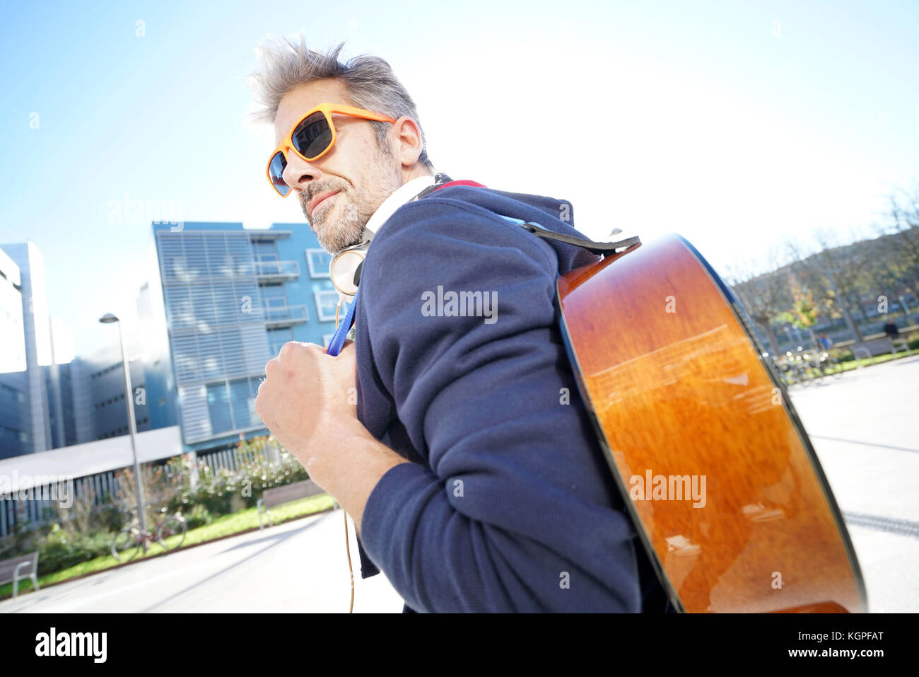 Musician walking with guitar in the back, urban life Stock Photo - Alamy