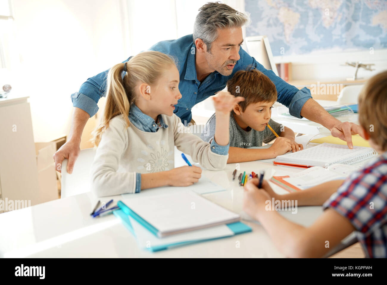 Teacher with kids in class giving writing lesson Stock Photo - Alamy