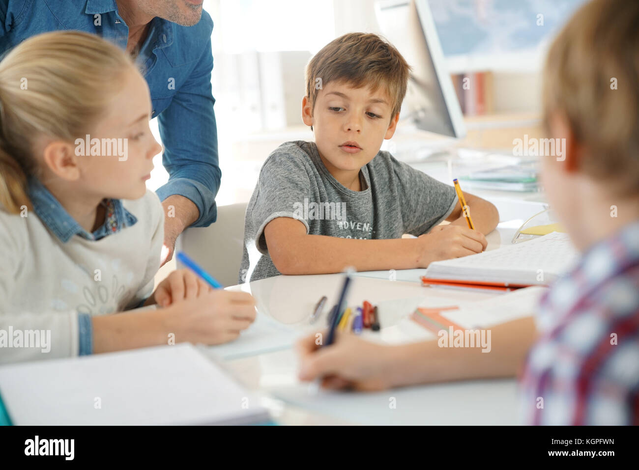 Kids writing notes in classroom Stock Photo - Alamy