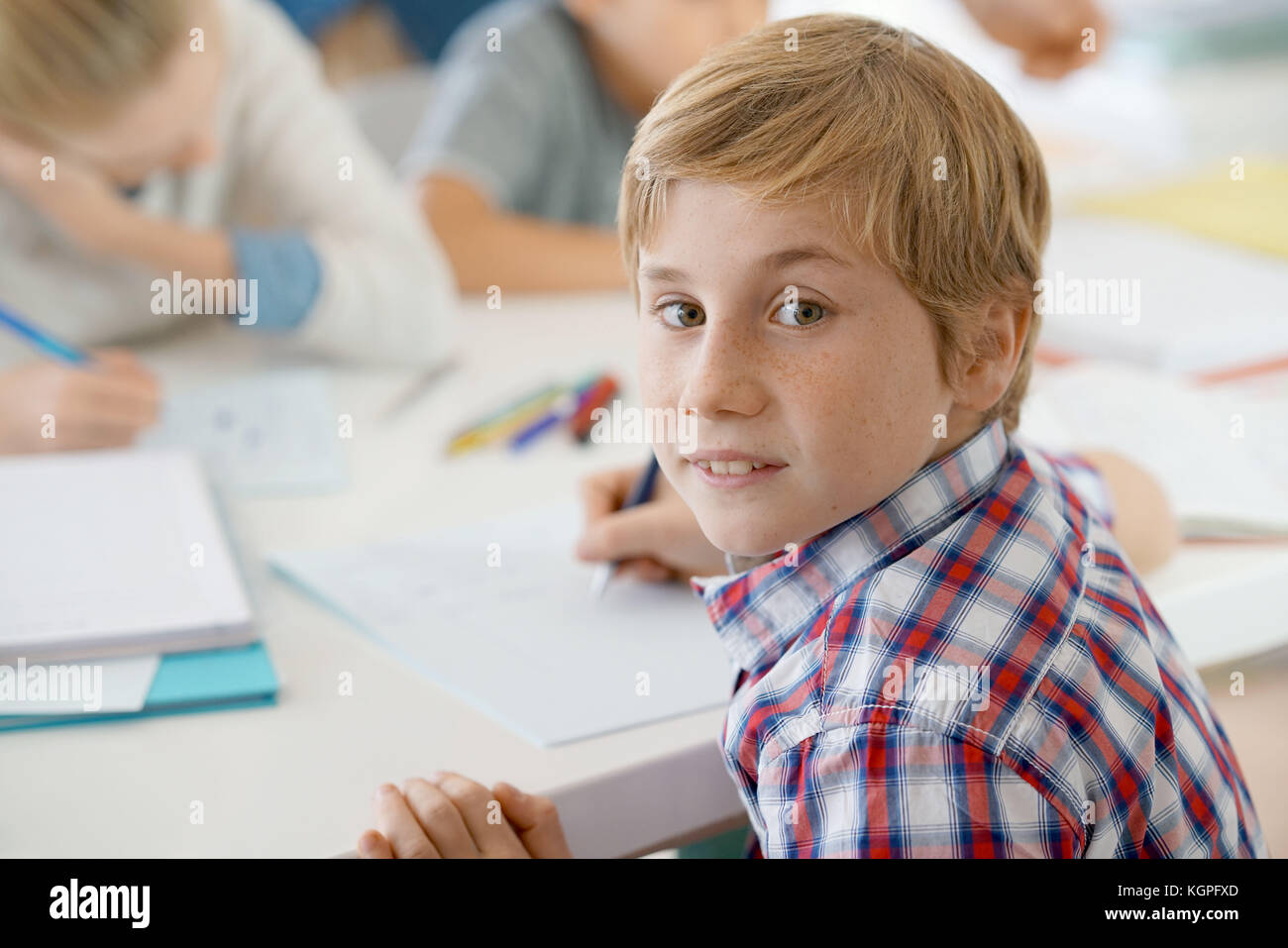 Portrait of pupil in school class taking notes during writing lesson ...
