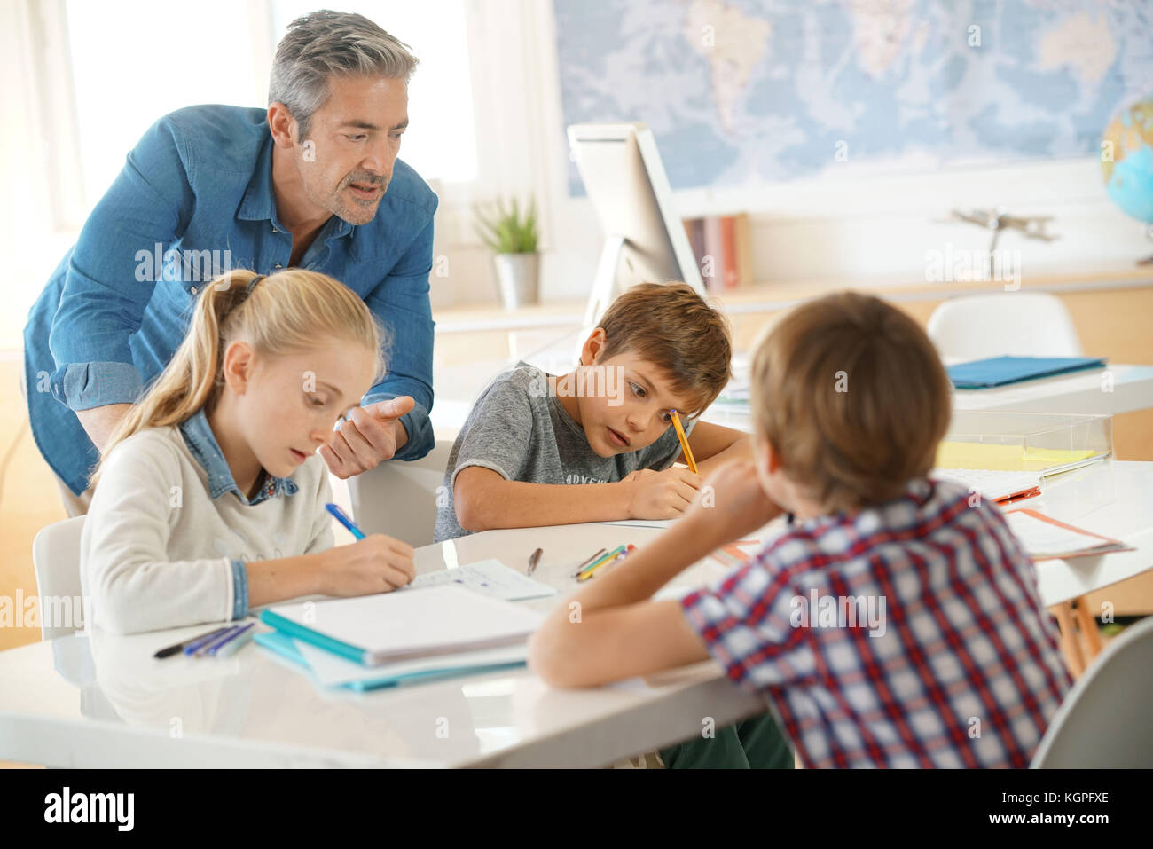 Teacher with kids in class giving writing lesson Stock Photo - Alamy