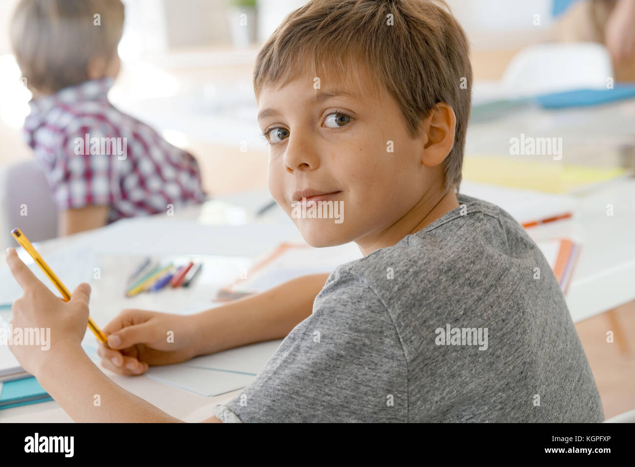 Portrait of pupil in school class taking notes during writing lesson ...