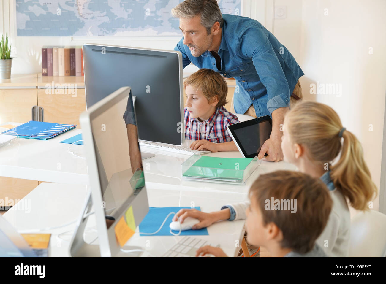 Teacher with school kids in computer laboratory Stock Photo - Alamy