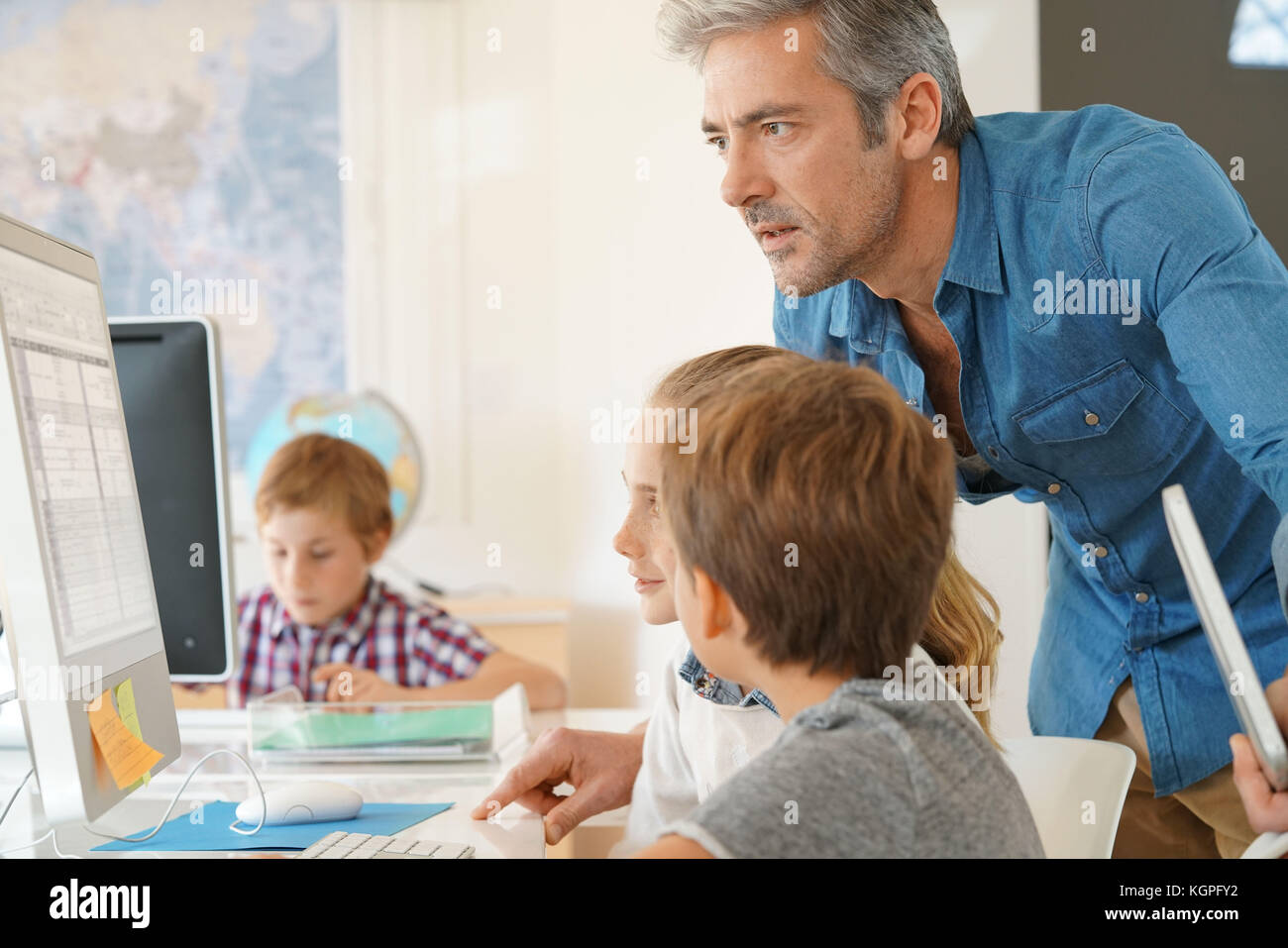 Teacher with school kids in computer laboratory Stock Photo - Alamy