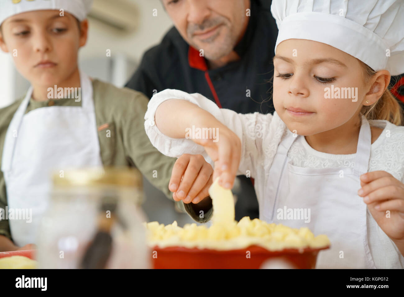 Pastry chef watching kids preparing apple pie Stock Photo - Alamy