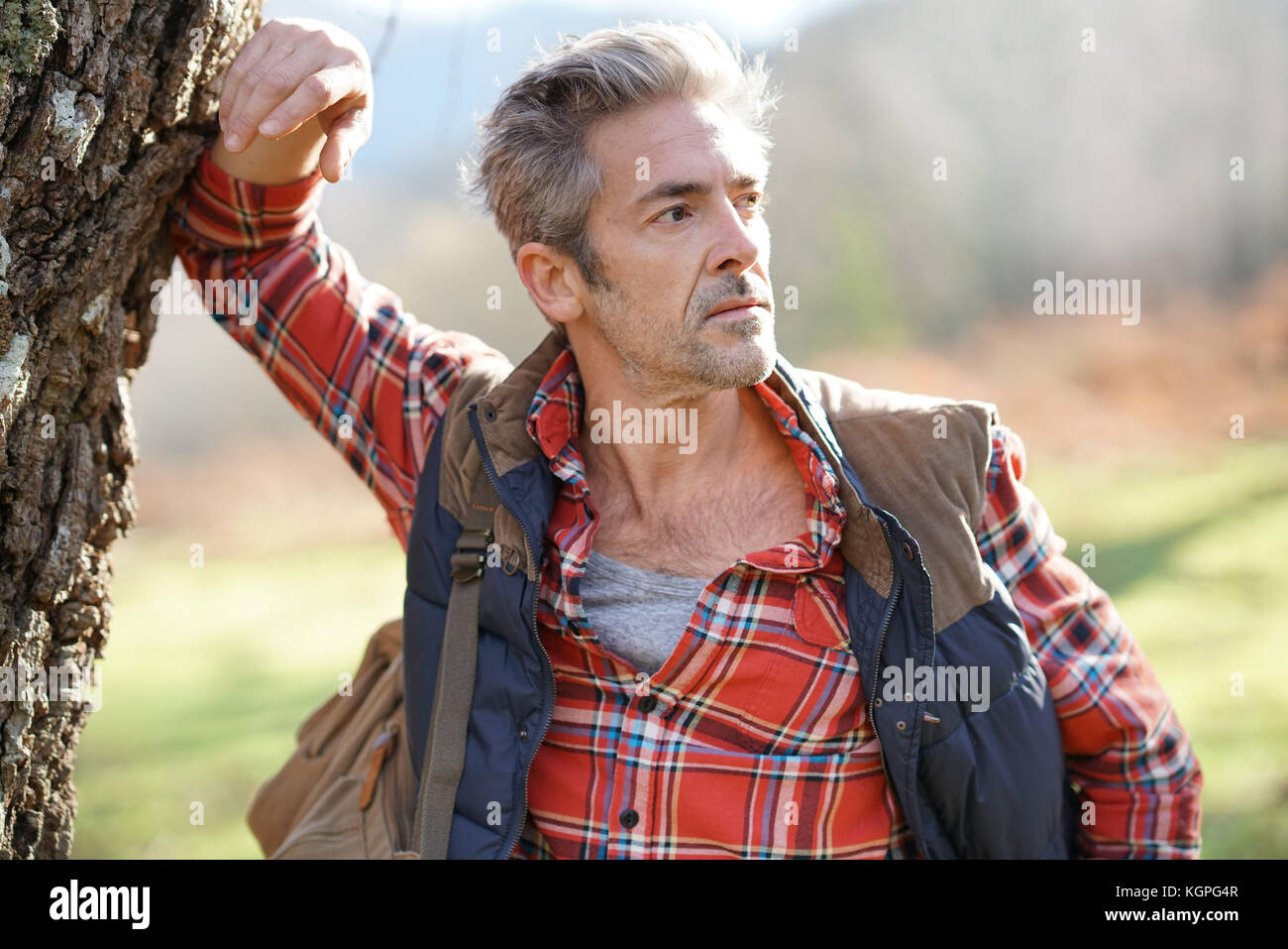 Hiker relaxing by tree on trekking journey Stock Photo - Alamy