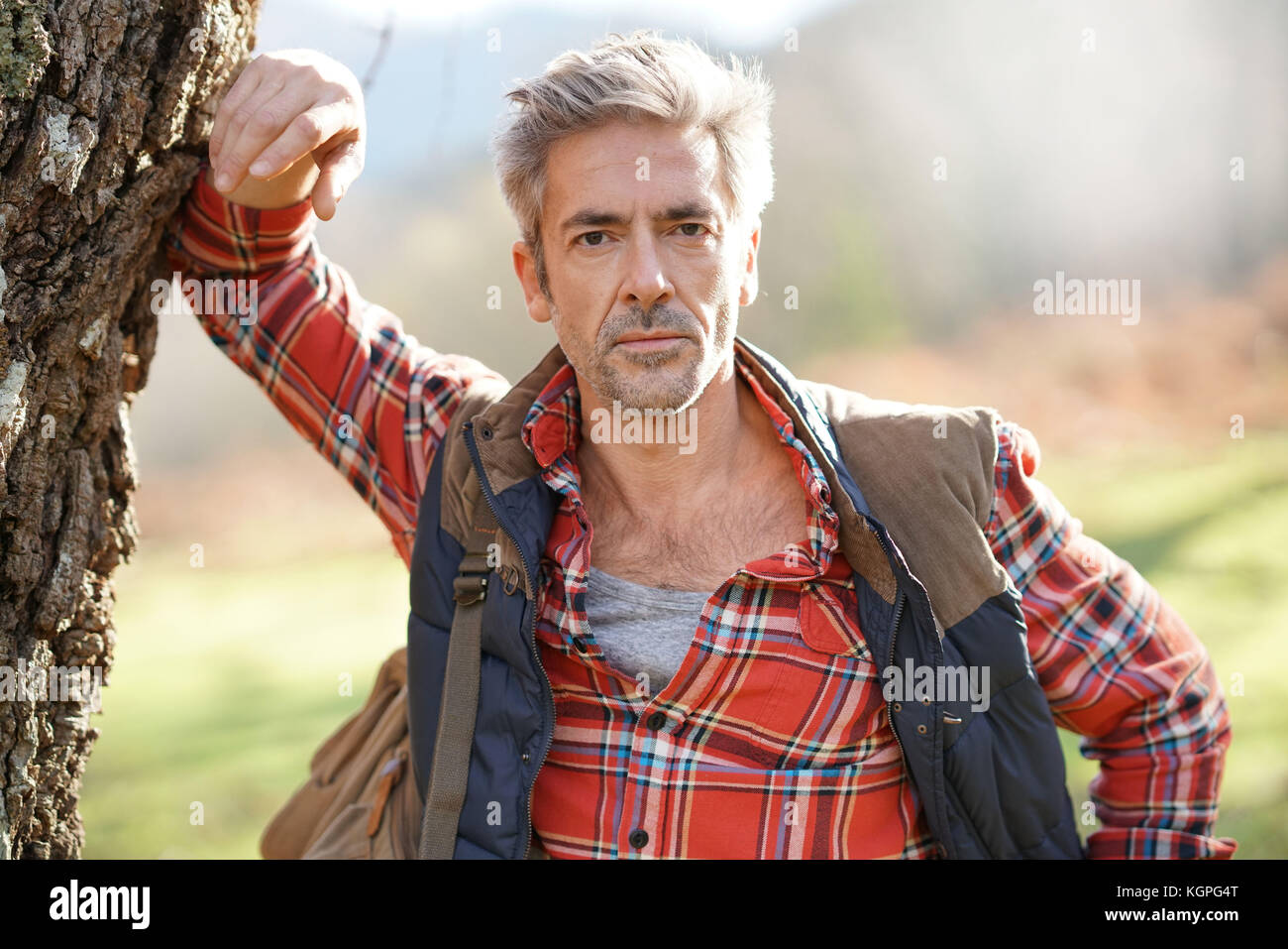 Hiker relaxing by tree on trekking journey Stock Photo - Alamy