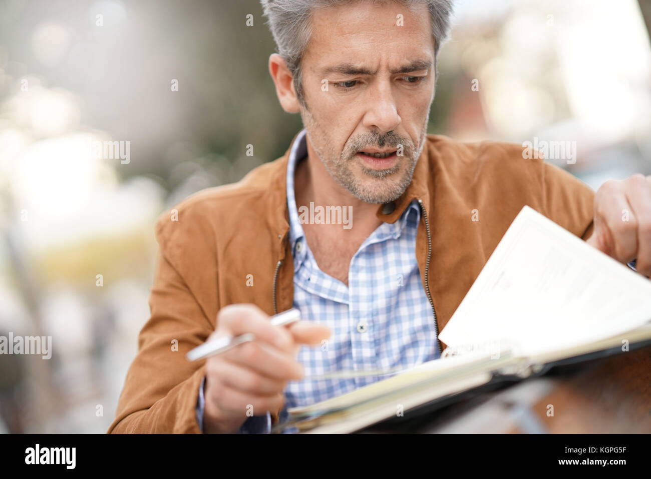 Businessman sitting on public bench, writing on agenda Stock Photo - Alamy