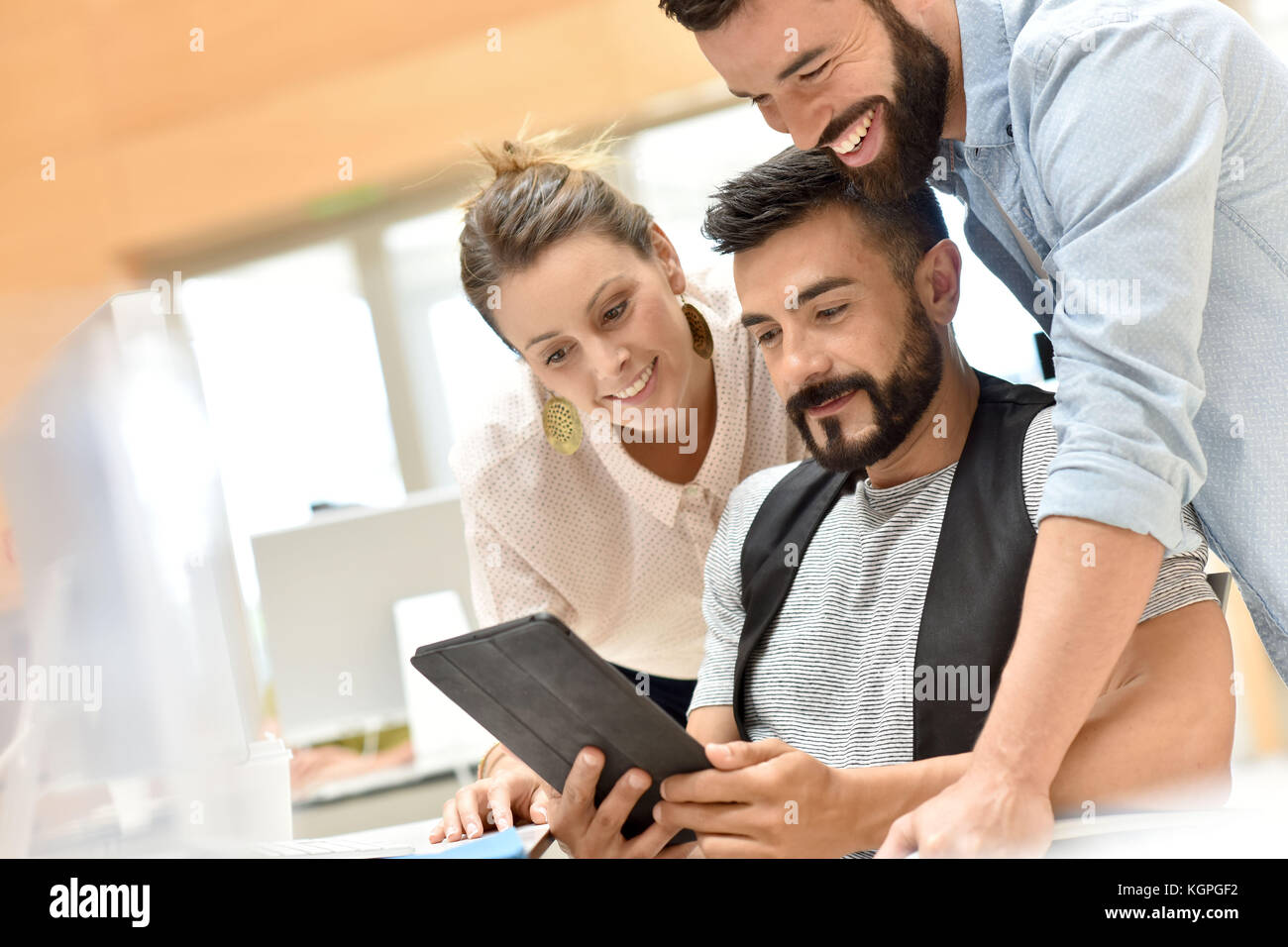 Team of cheerful designers working with tablet Stock Photo - Alamy