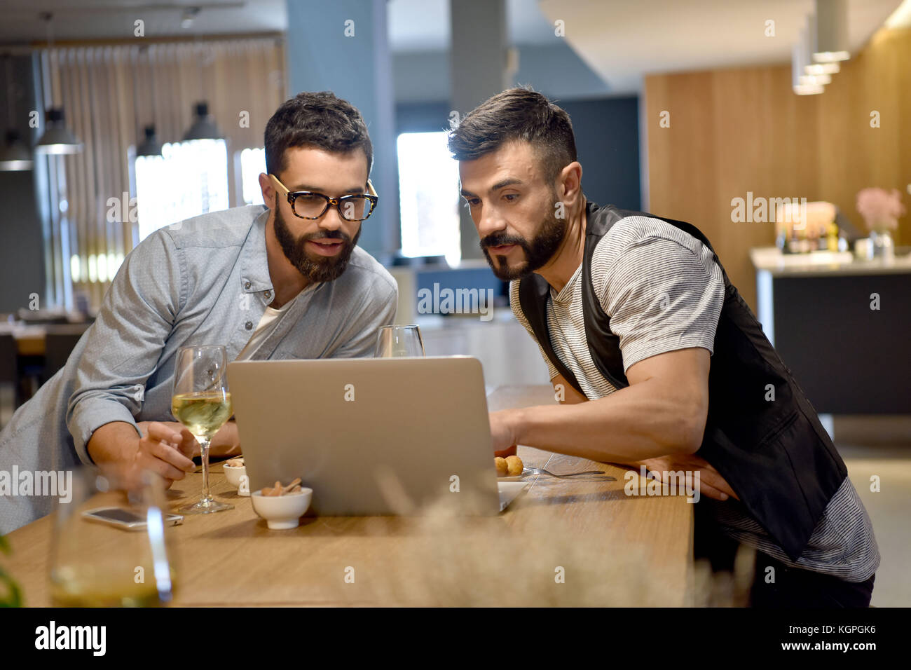 Trendy guys in bar connected with laptop Stock Photo - Alamy