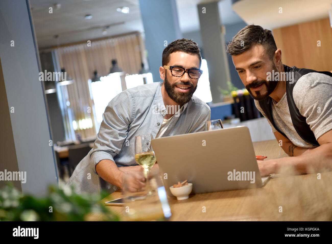Trendy guys in bar connected with laptop Stock Photo - Alamy