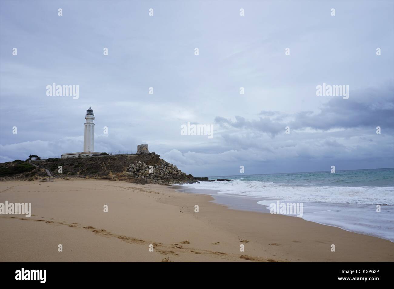 Lighthouse on beach with waves and clouds Stock Photo - Alamy