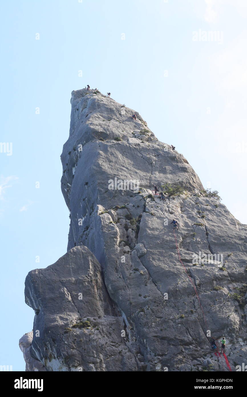 A big rock with mountain climbers heading top the summit, seen from the ...