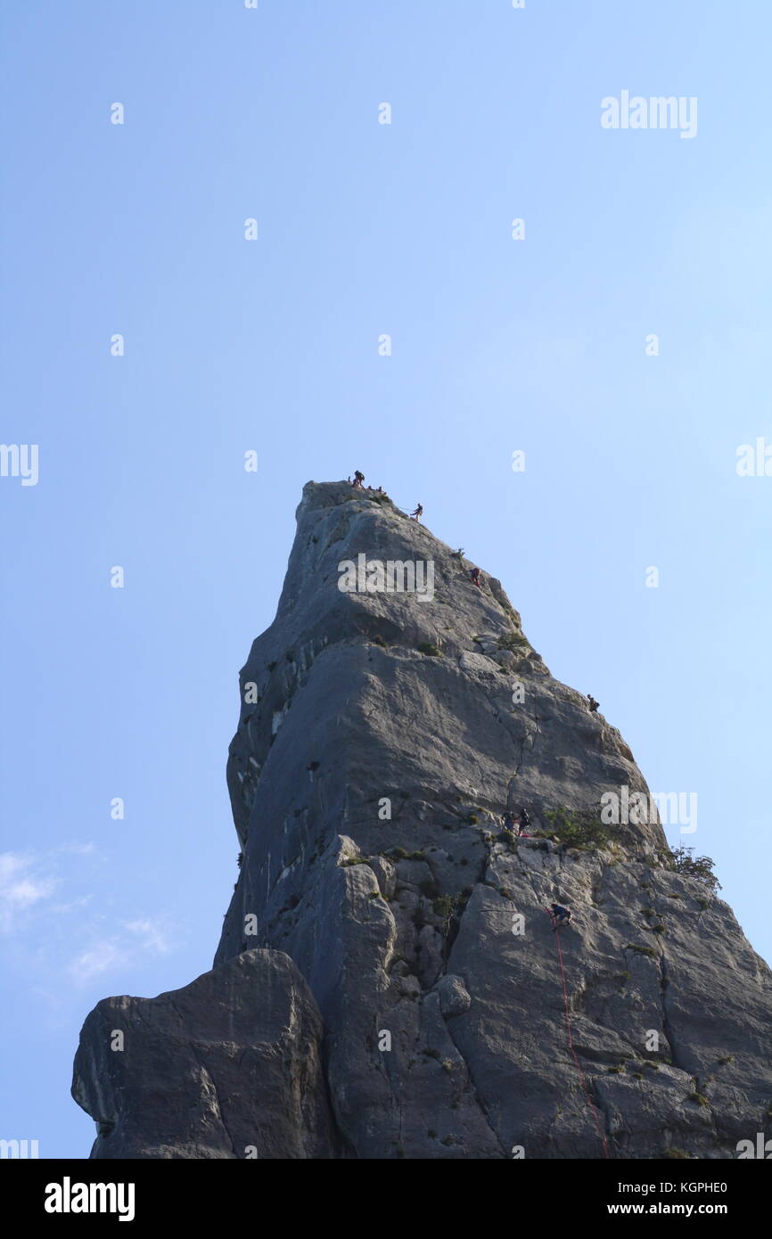 A big rock with mountain climbers heading top the summit, seen from the ...