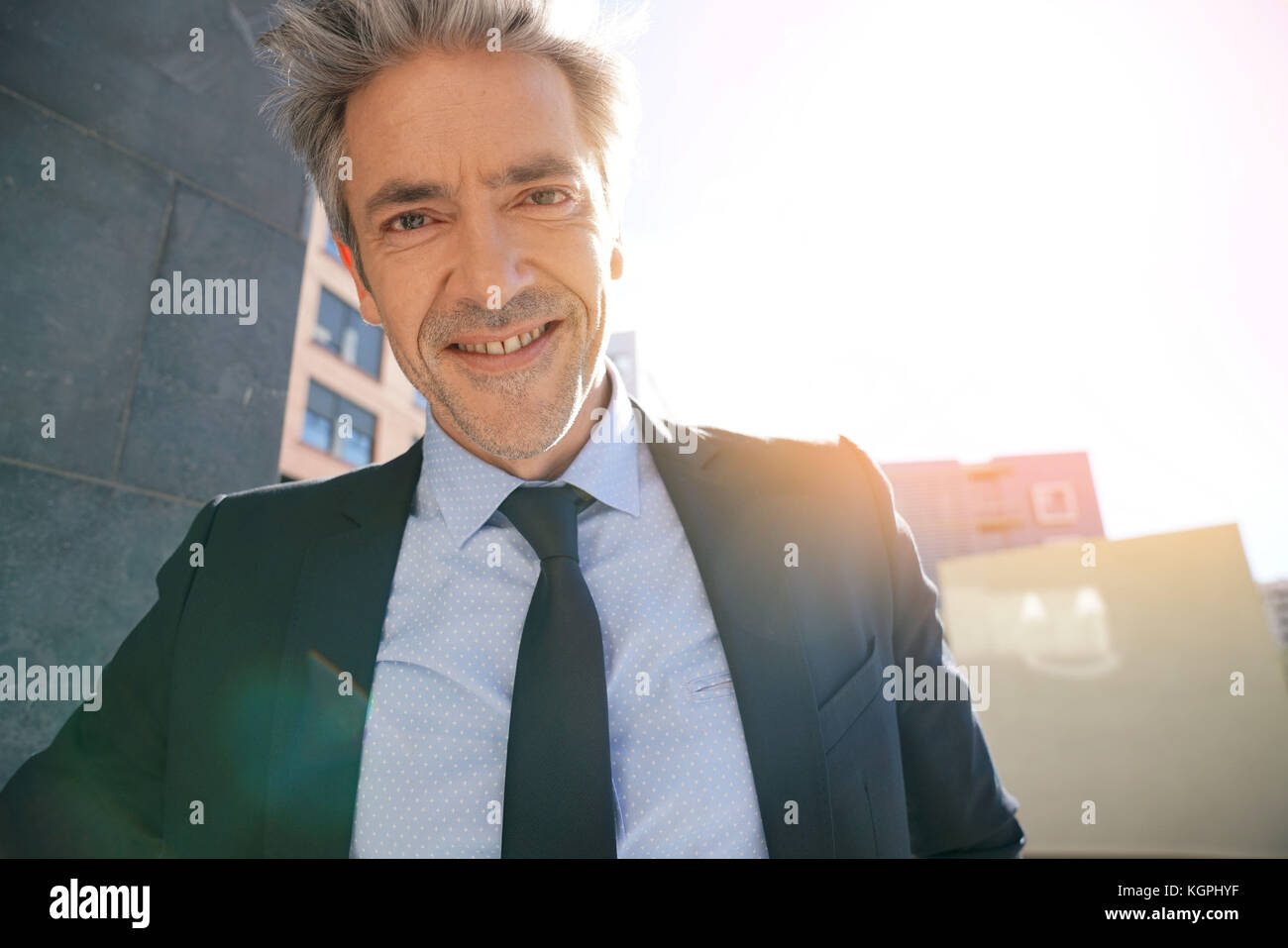 Portrait of businessman waiting outside building, leant on wall Stock ...