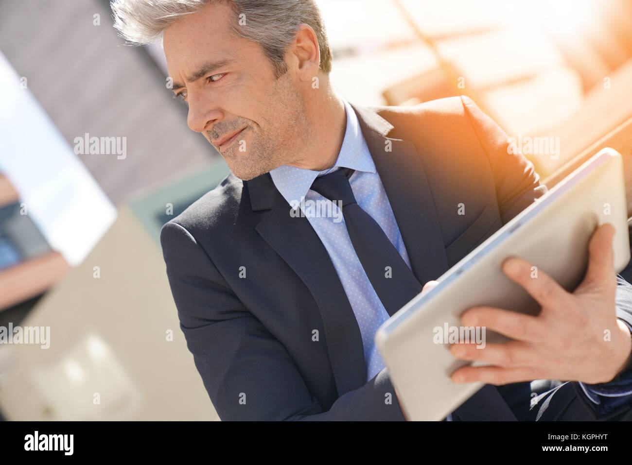 Businessman working on digital tablet in front of office building Stock ...