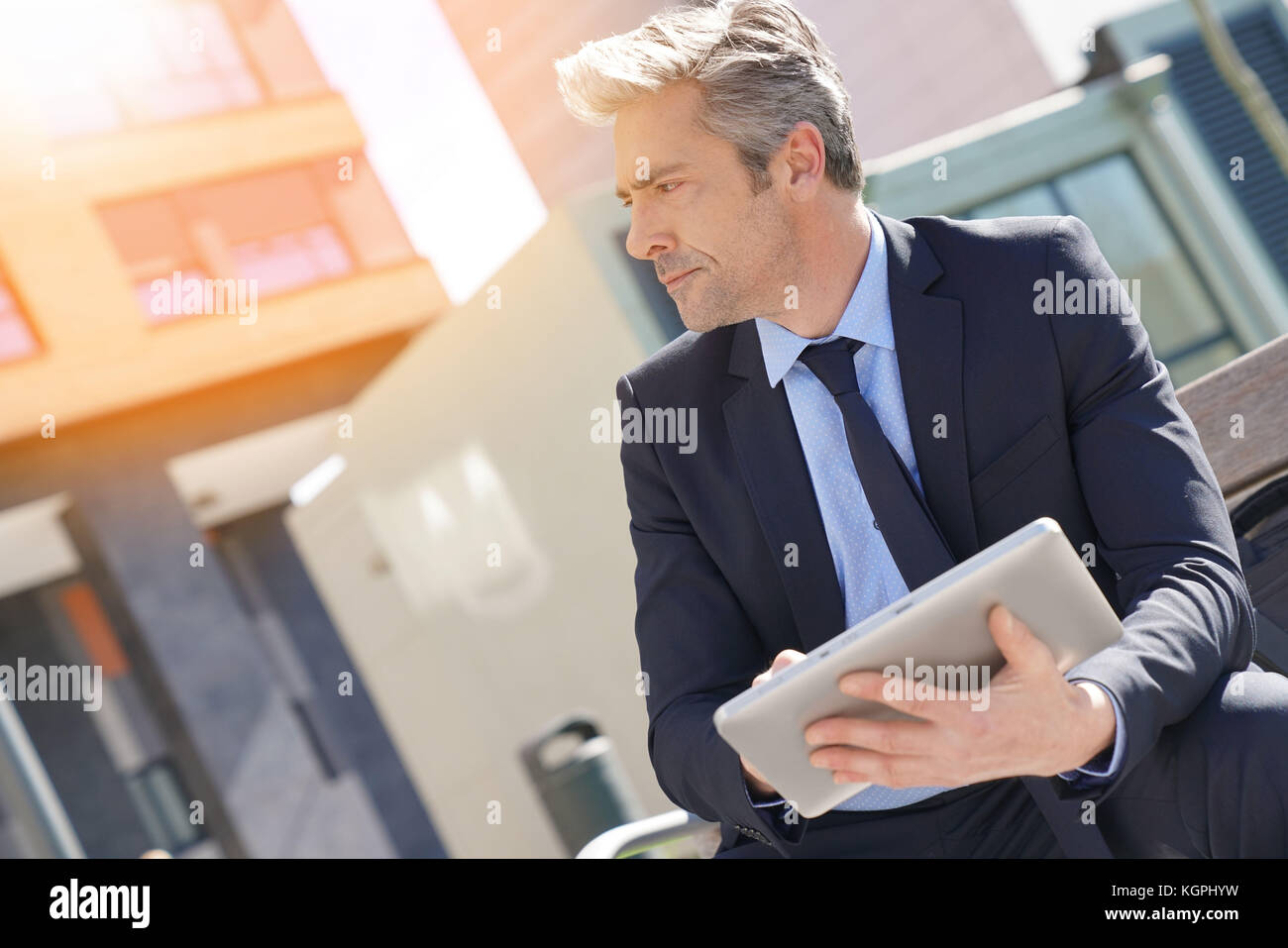 Businessman working on digital tablet in front of office building Stock ...