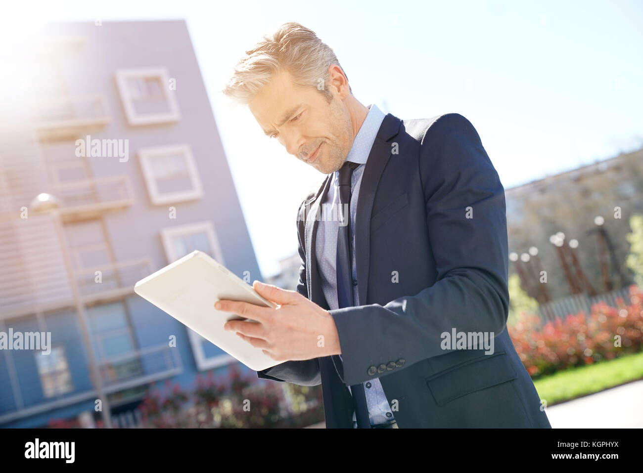 Businessman working on digital tablet in front of office building Stock ...