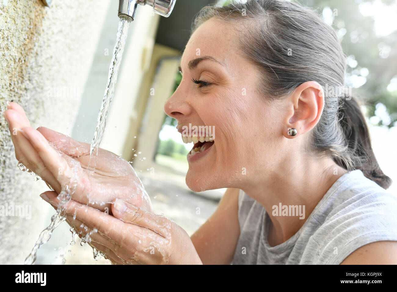 Portrait of cheerful girl drinking water from faucet Stock Photo - Alamy
