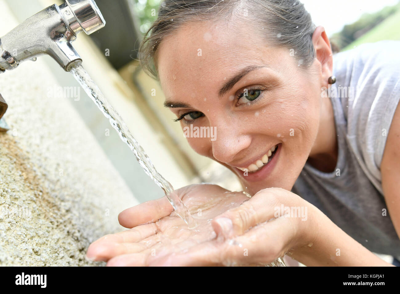 Portrait of cheerful girl drinking water from faucet Stock Photo - Alamy