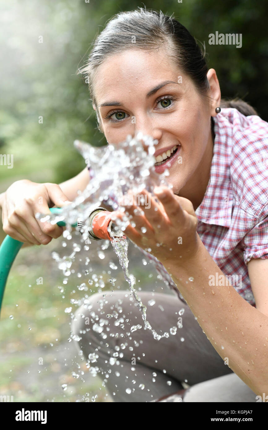 Woman spreading water from garden hose Stock Photo - Alamy