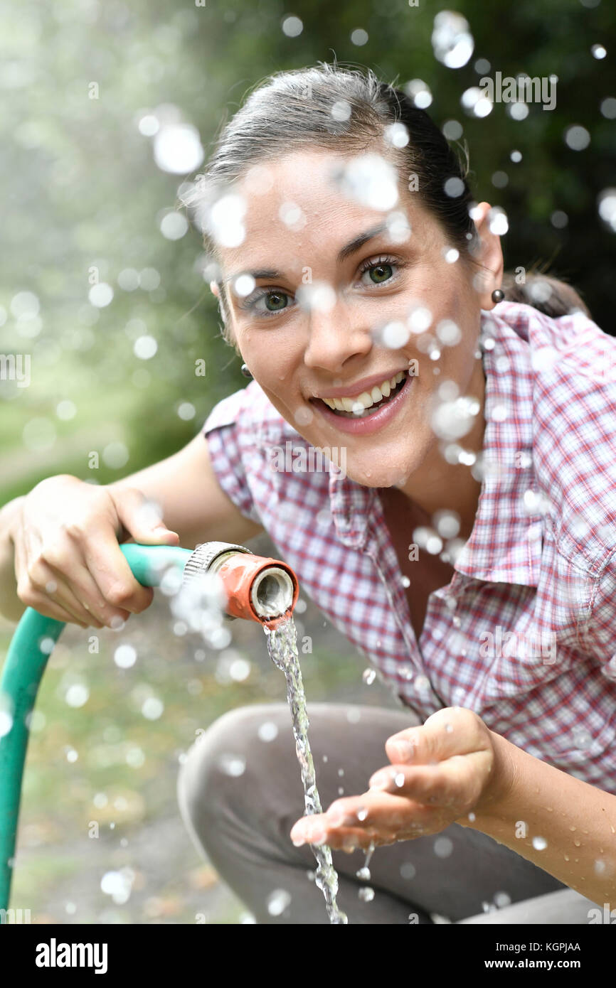 Woman spreading water from garden hose Stock Photo - Alamy