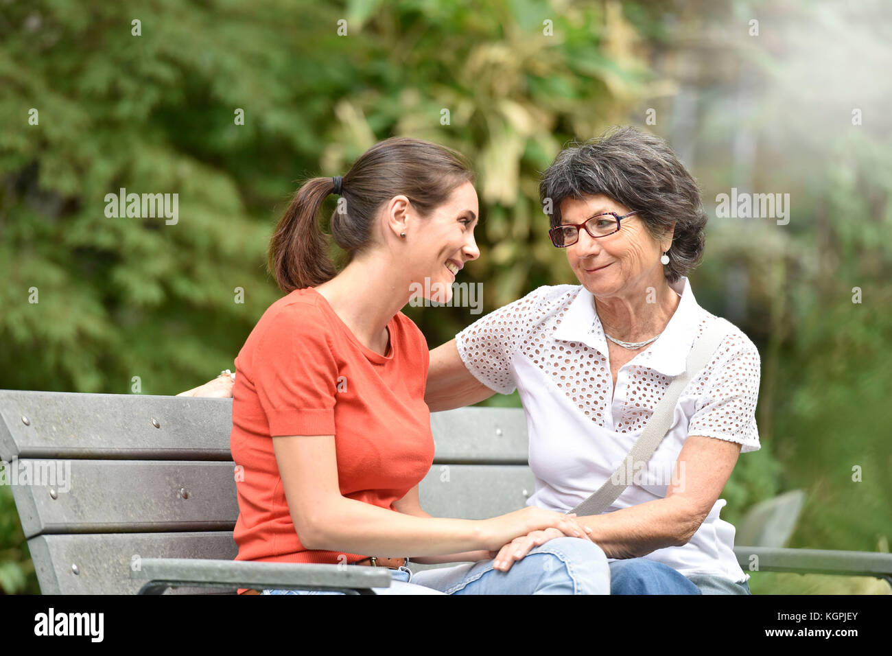 Senior woman with carer sitting on bench at the park Stock Photo - Alamy