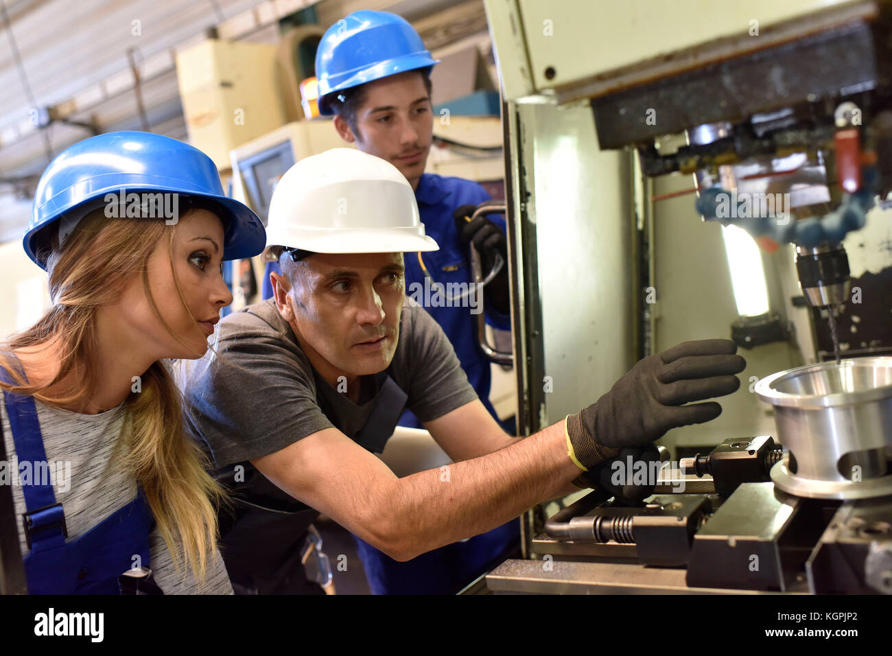 Metal worker teaching trainees on machine use Stock Photo - Alamy