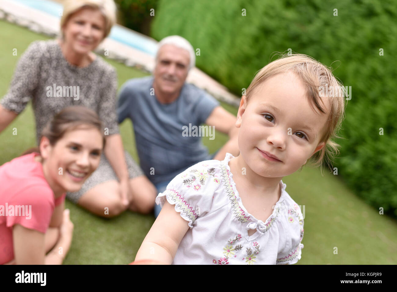 Portrait of cute 2-year-old girl, family in background Stock Photo - Alamy
