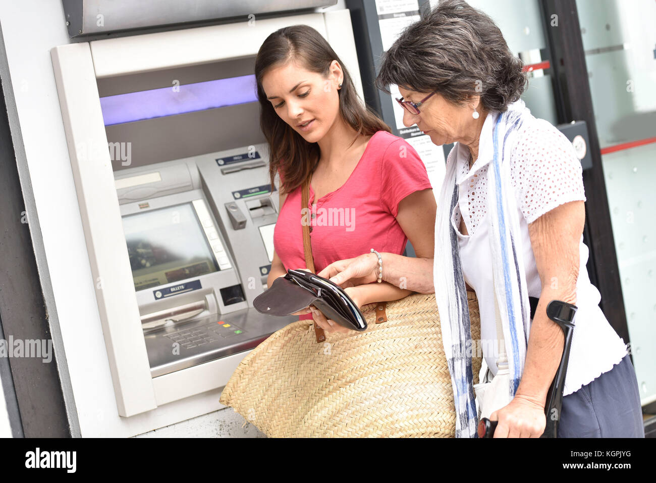 Home carer and disabled woman getting cash from bank Stock Photo - Alamy