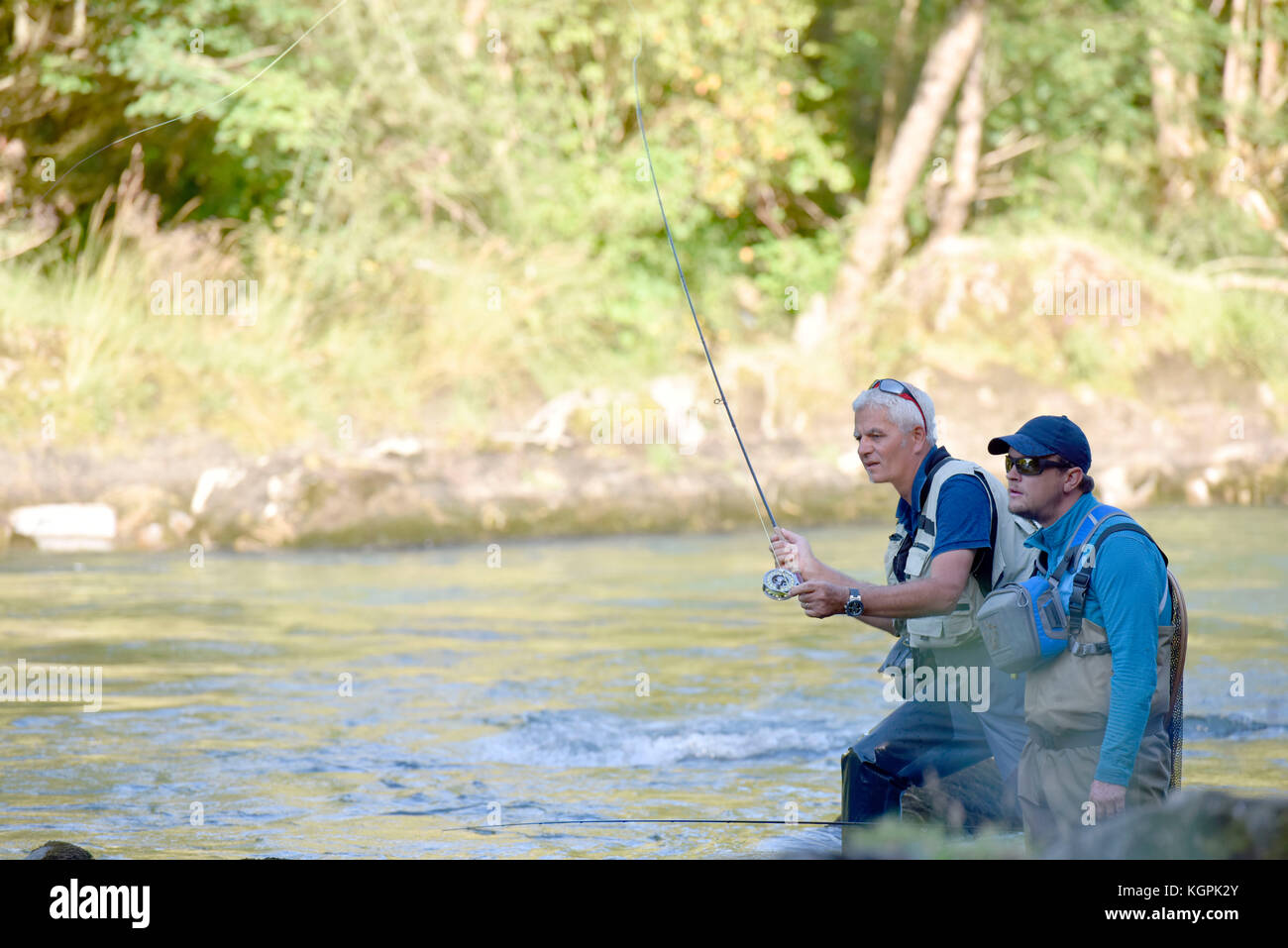 Flyfisherman with fishing guide in river Stock Photo - Alamy