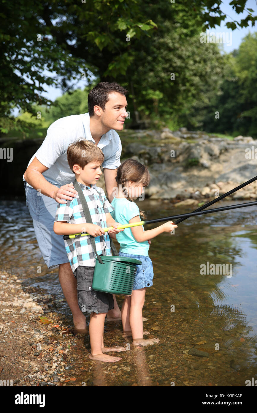 Man teaching kids how to fish in river Stock Photo - Alamy