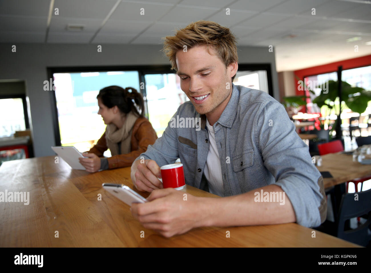 Young man in coffee shop wonnected on smartphone Stock Photo - Alamy