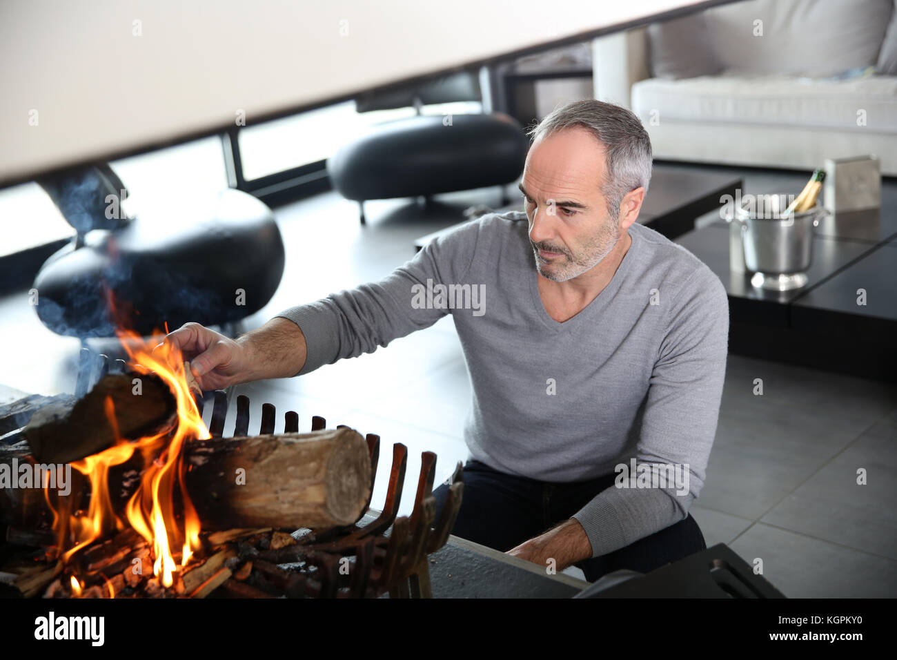 Mature man in modern house preparing fire Stock Photo - Alamy