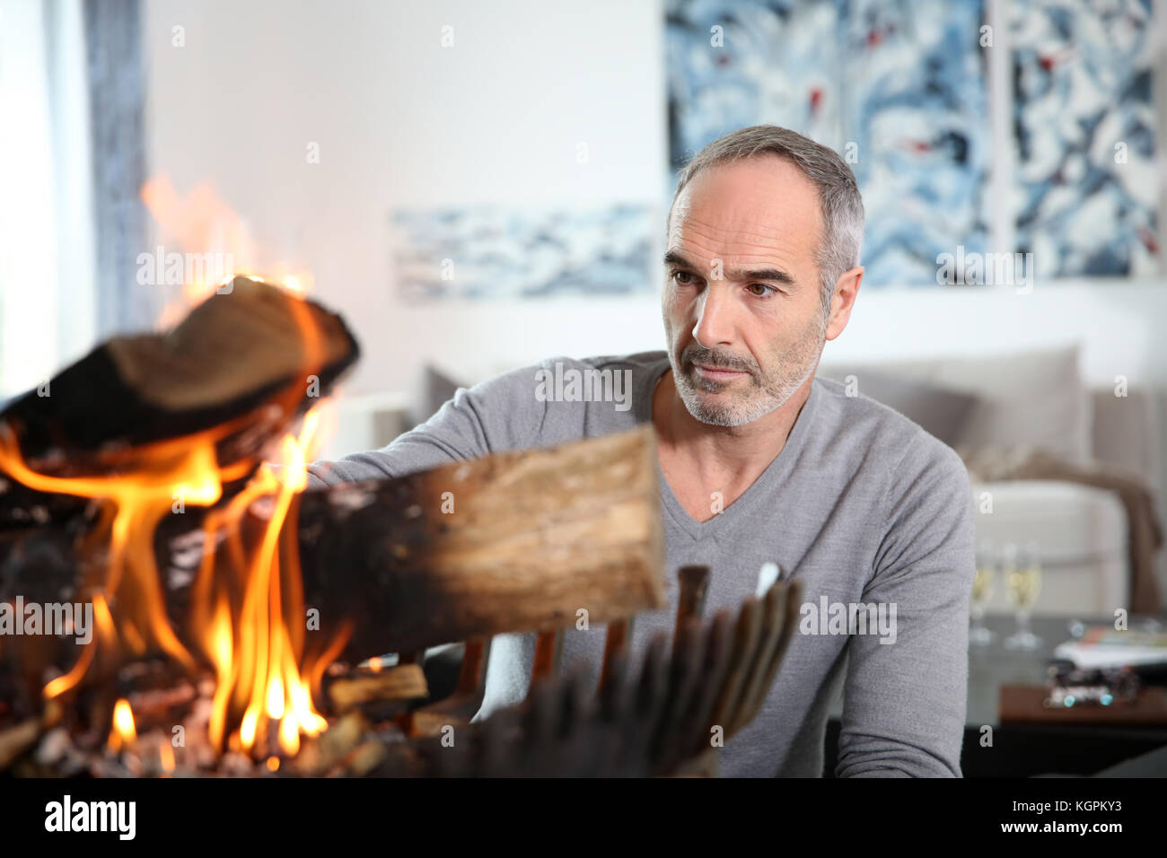 Mature man in modern house preparing fire Stock Photo - Alamy