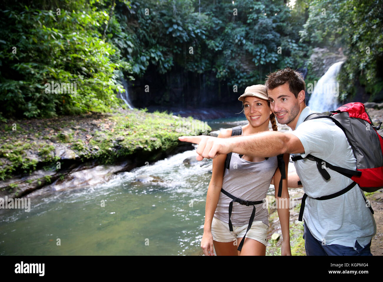 Trekkers reaching waterfall in natural landscape Stock Photo - Alamy
